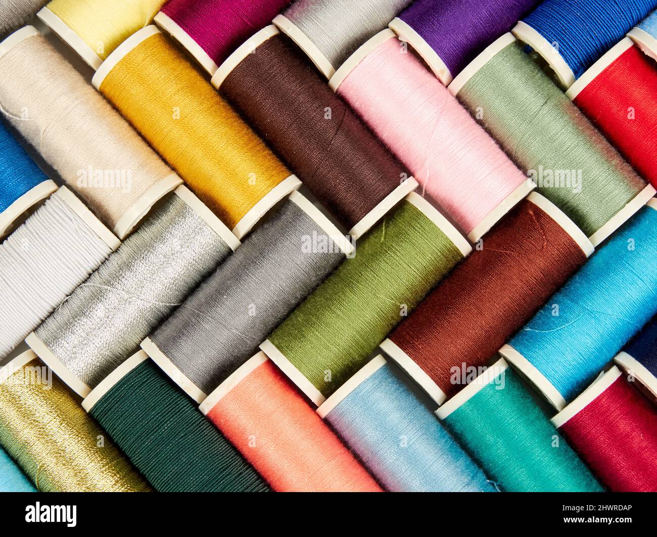 Assortment of spools with colored sewing thread on white background ...