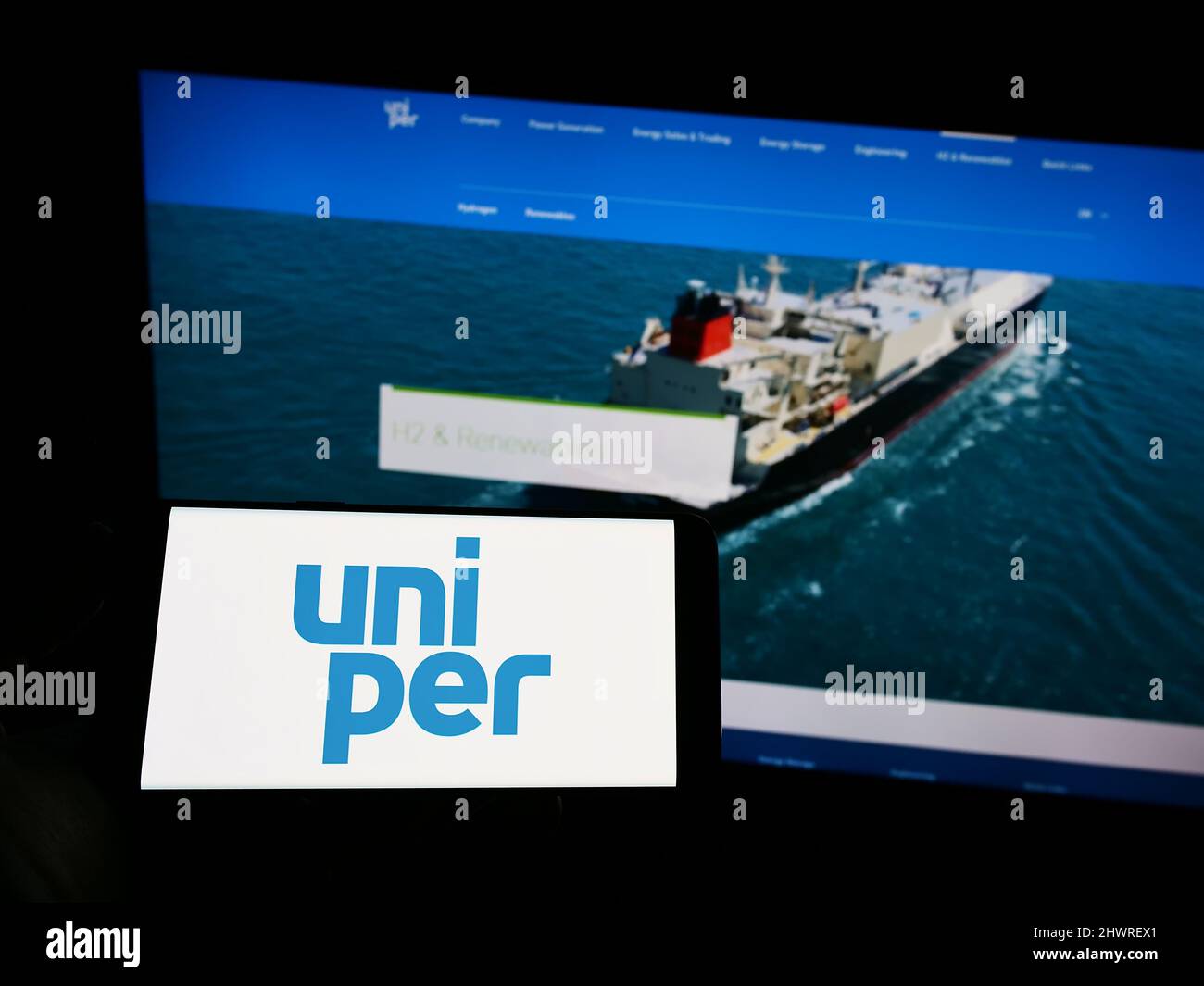 Person holding cellphone with logo of German energy company Uniper SE ...