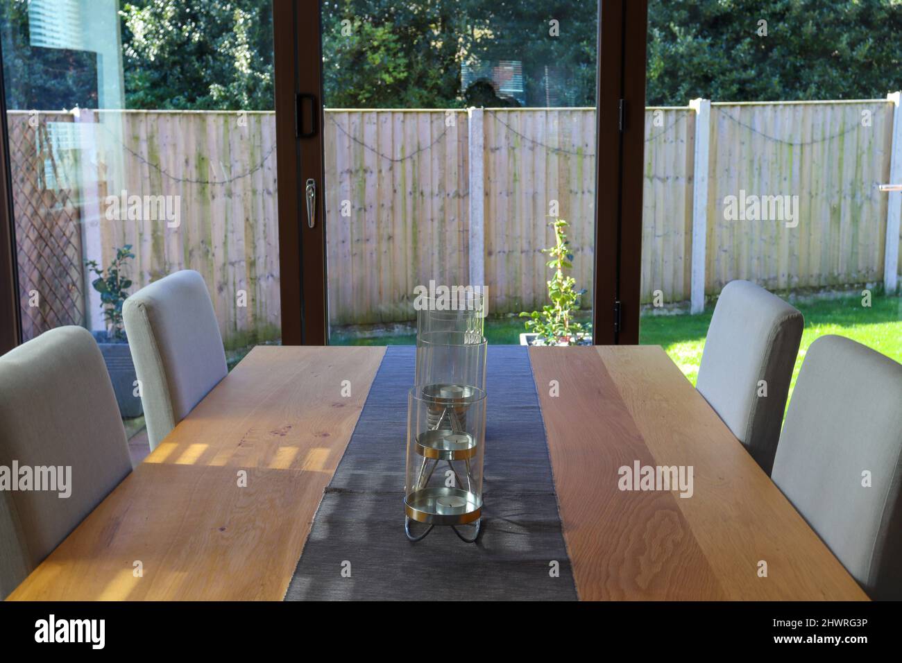 View down dining table with candle holder, looking toward bi-fold doors ...