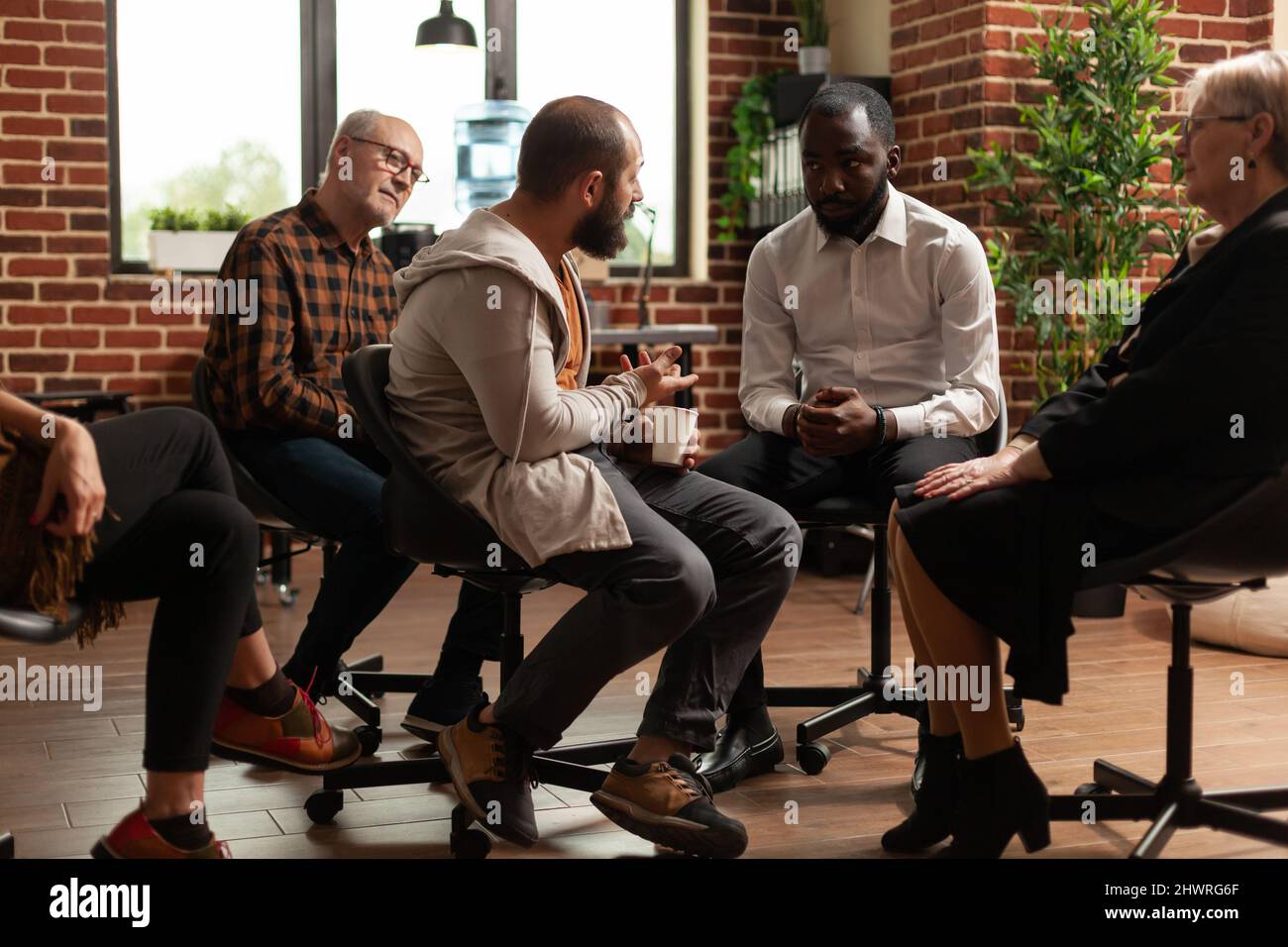 Multi ethnic group of people attending aa therapy meeting with ...