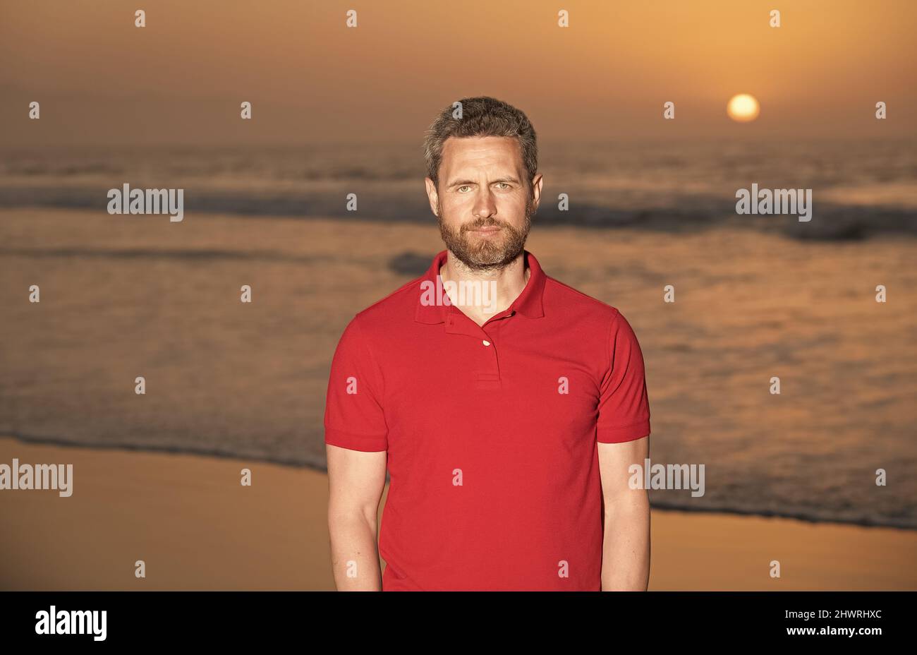 bearded handsome man in summer shirt on beach with sunset over sea ...