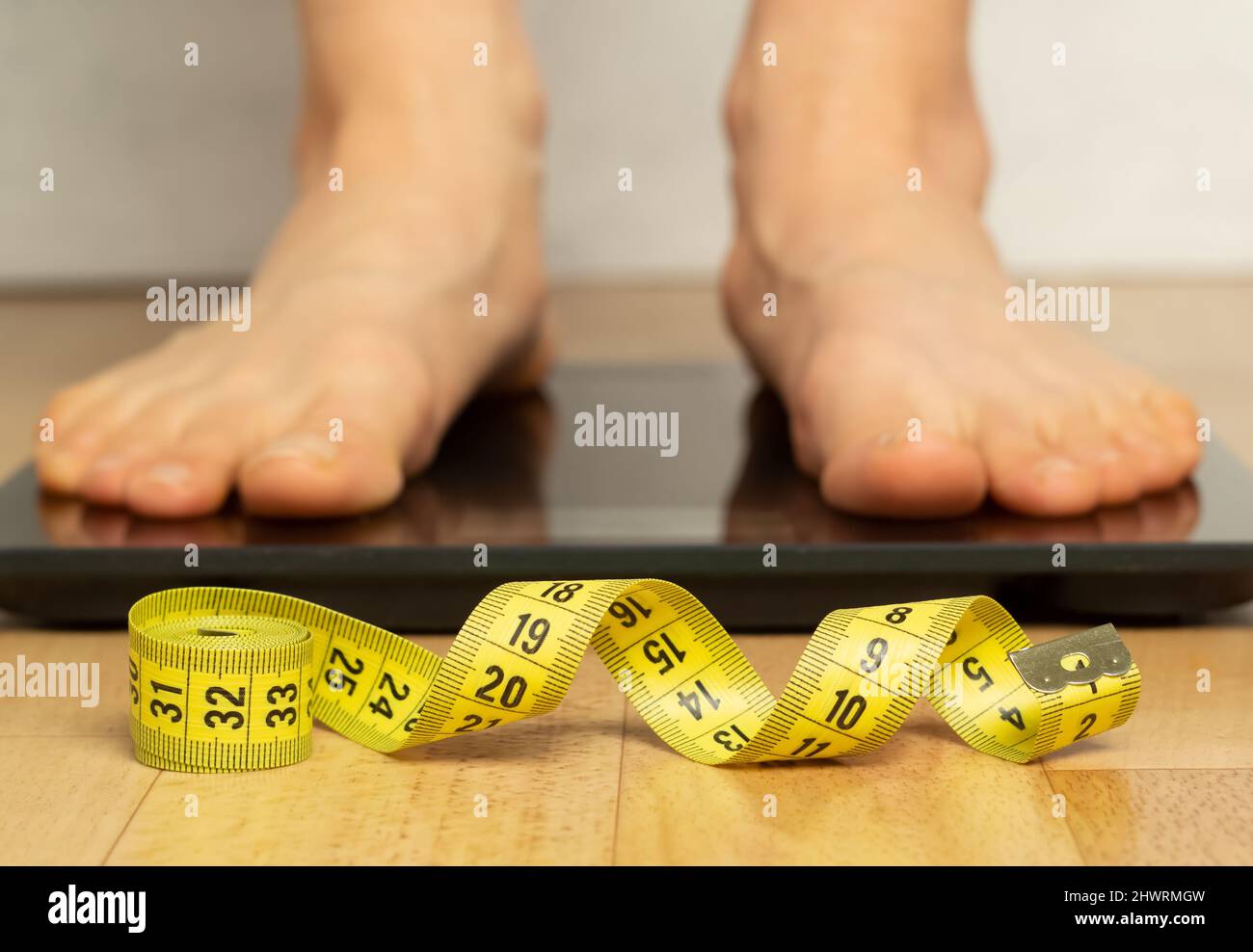Feet on floor scales with measuring tape. Overweight concept Stock ...