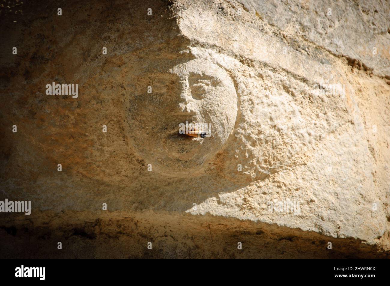 Smoking addiction. Stone human face (old building architectural detail ...