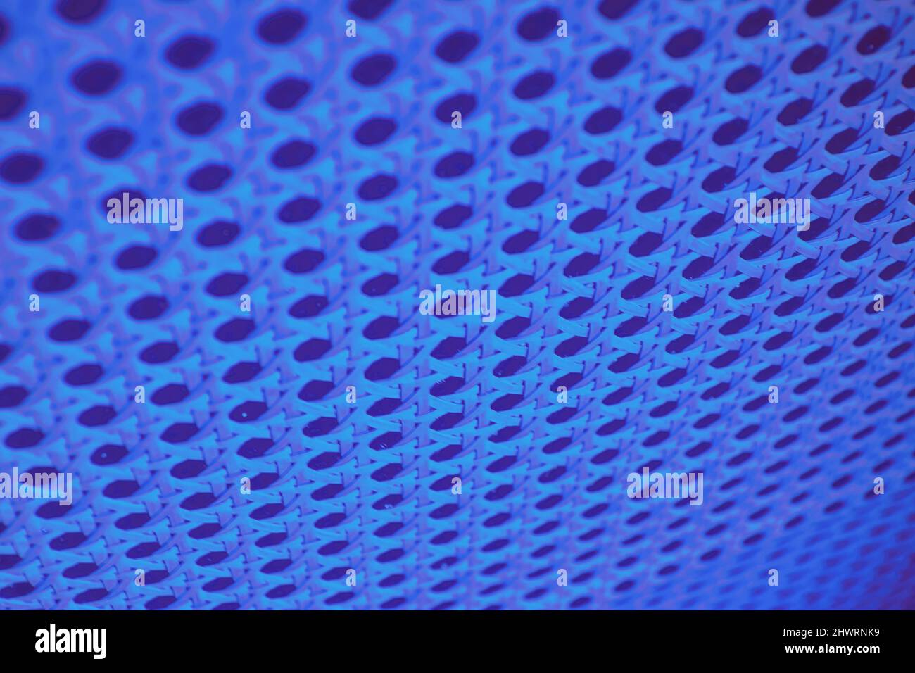 Abstract perforated wall background highlighted by blue neon led lights ...