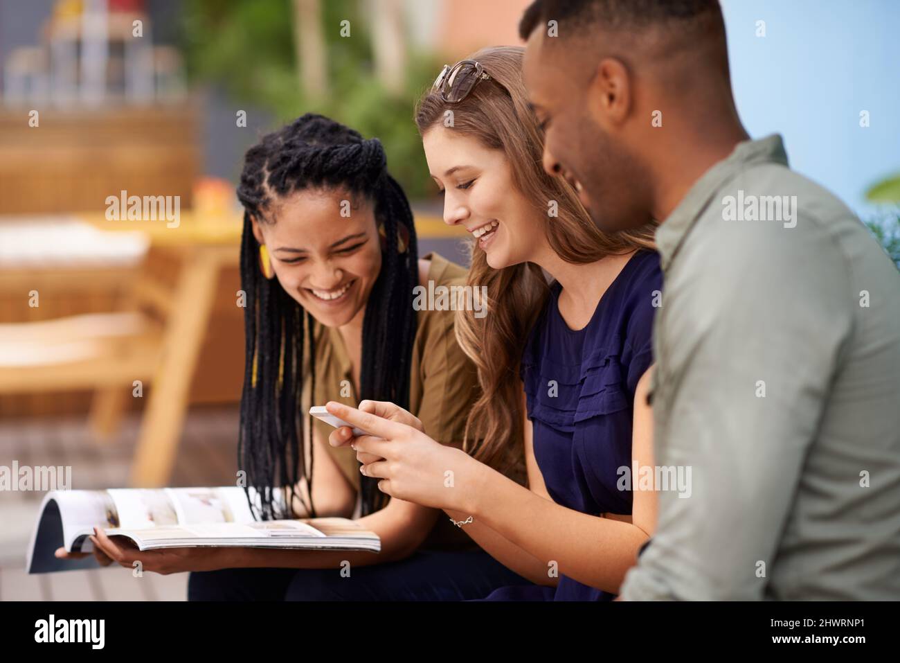 Print versus digital in the student world. Three friends reading from a ...