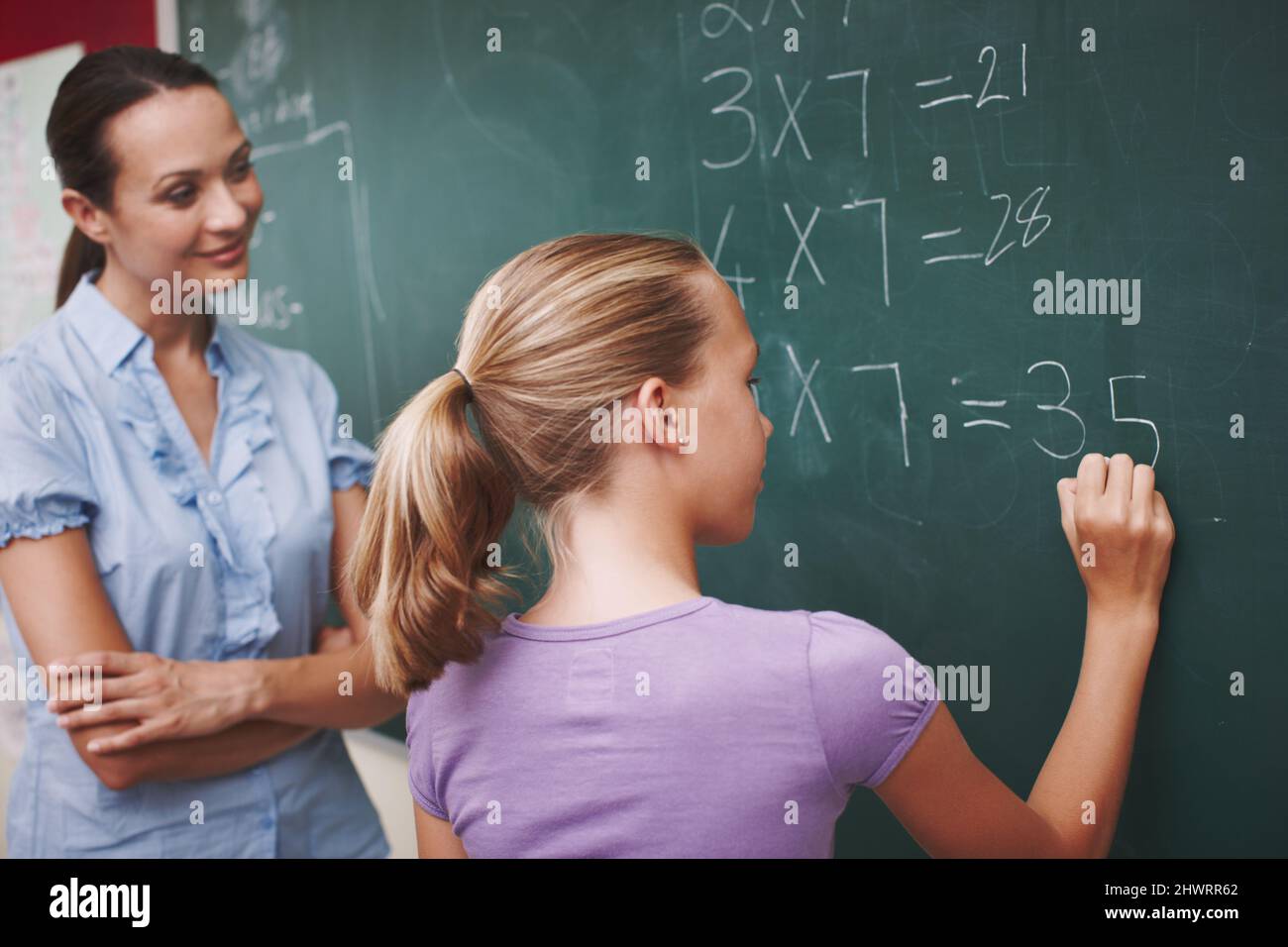 Improving on her mathematics. A pretty young teacher helping her ...
