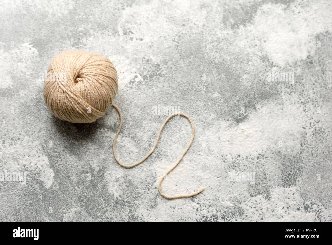 A tangle of beige-colored wool threads on a white concrete background ...