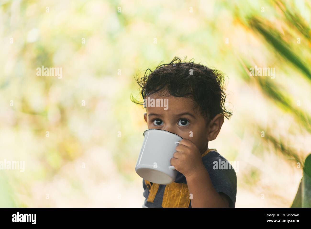 latin boy drinking coffee in a white cup, in a natural environment ...