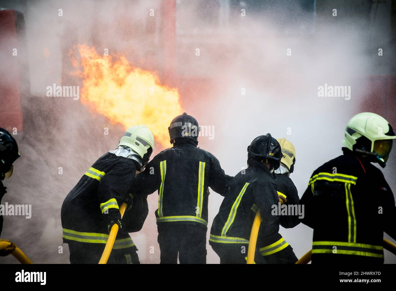 firefighters in training putting out a flame Stock Photo - Alamy