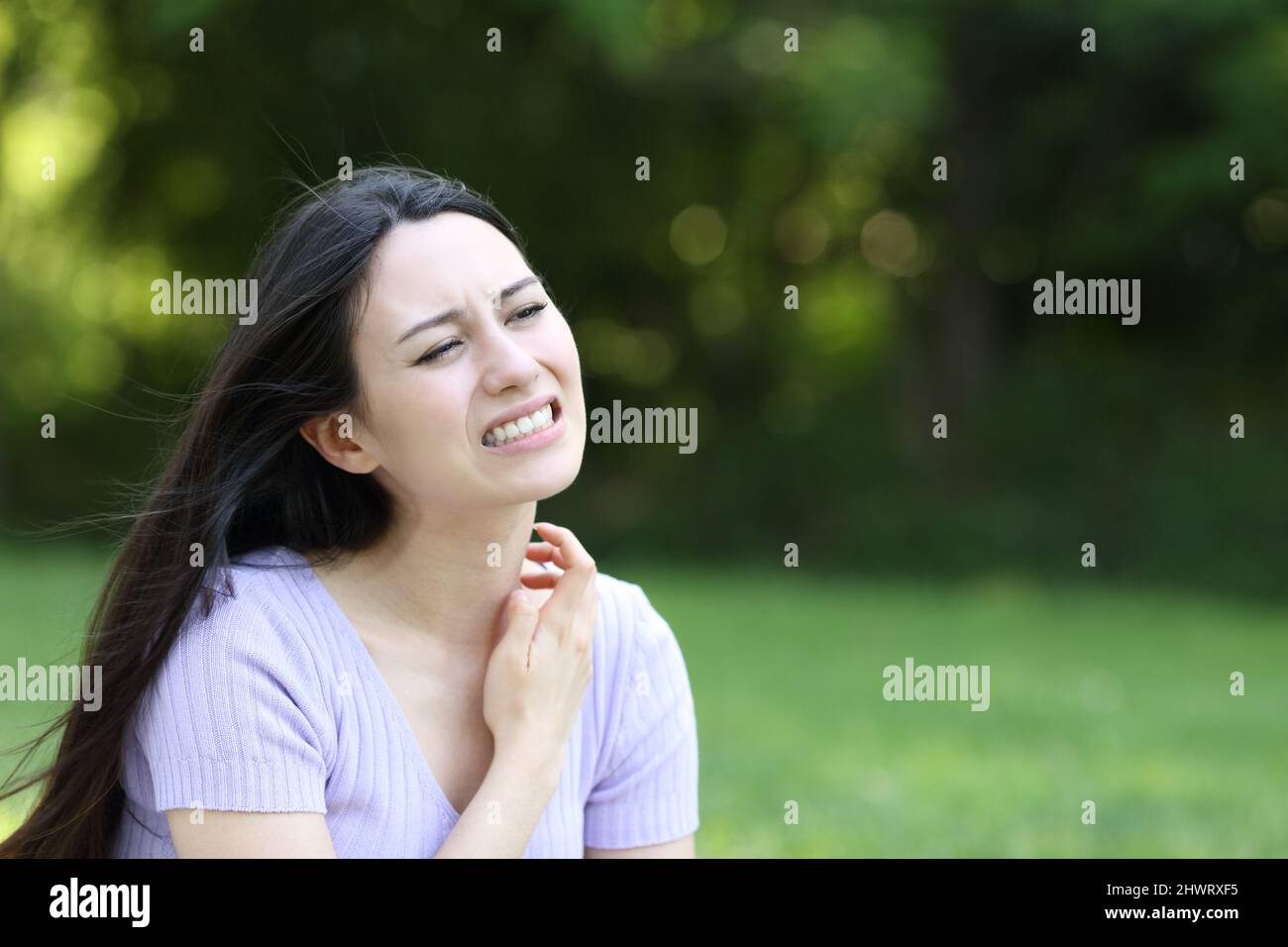 Stressed asian woman scratching neck sitting in a green park Stock ...