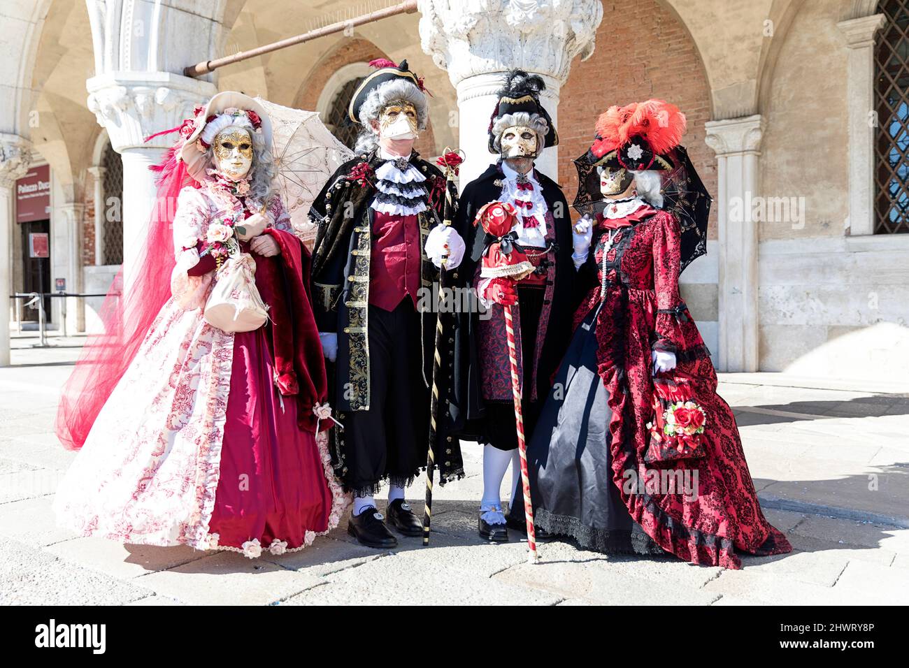 Tourists in beautiful traditional venetian costumes and masks posing at ...