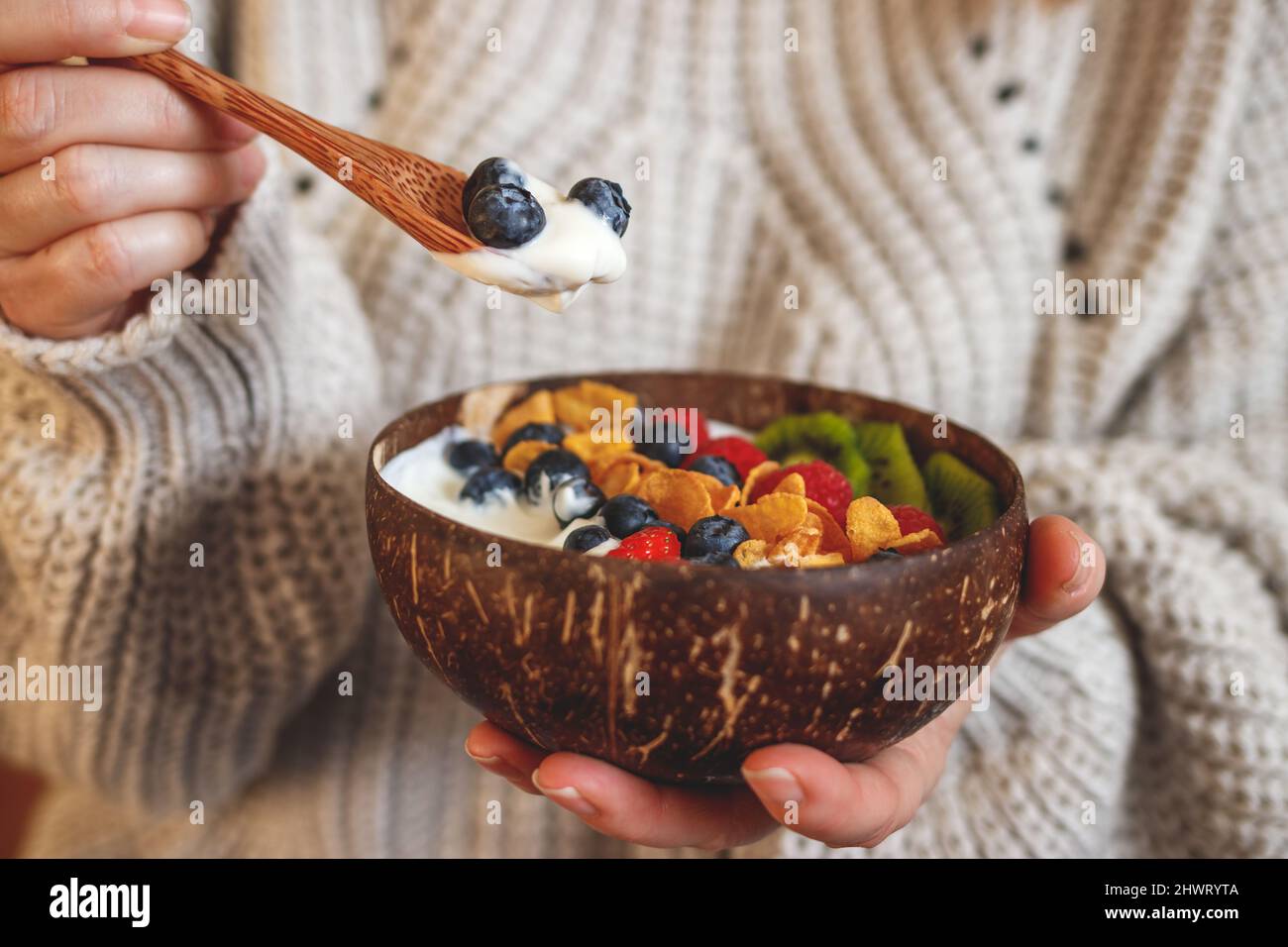 Woman eating healthy breakfast from coconut bowl. Yogurt with corn ...