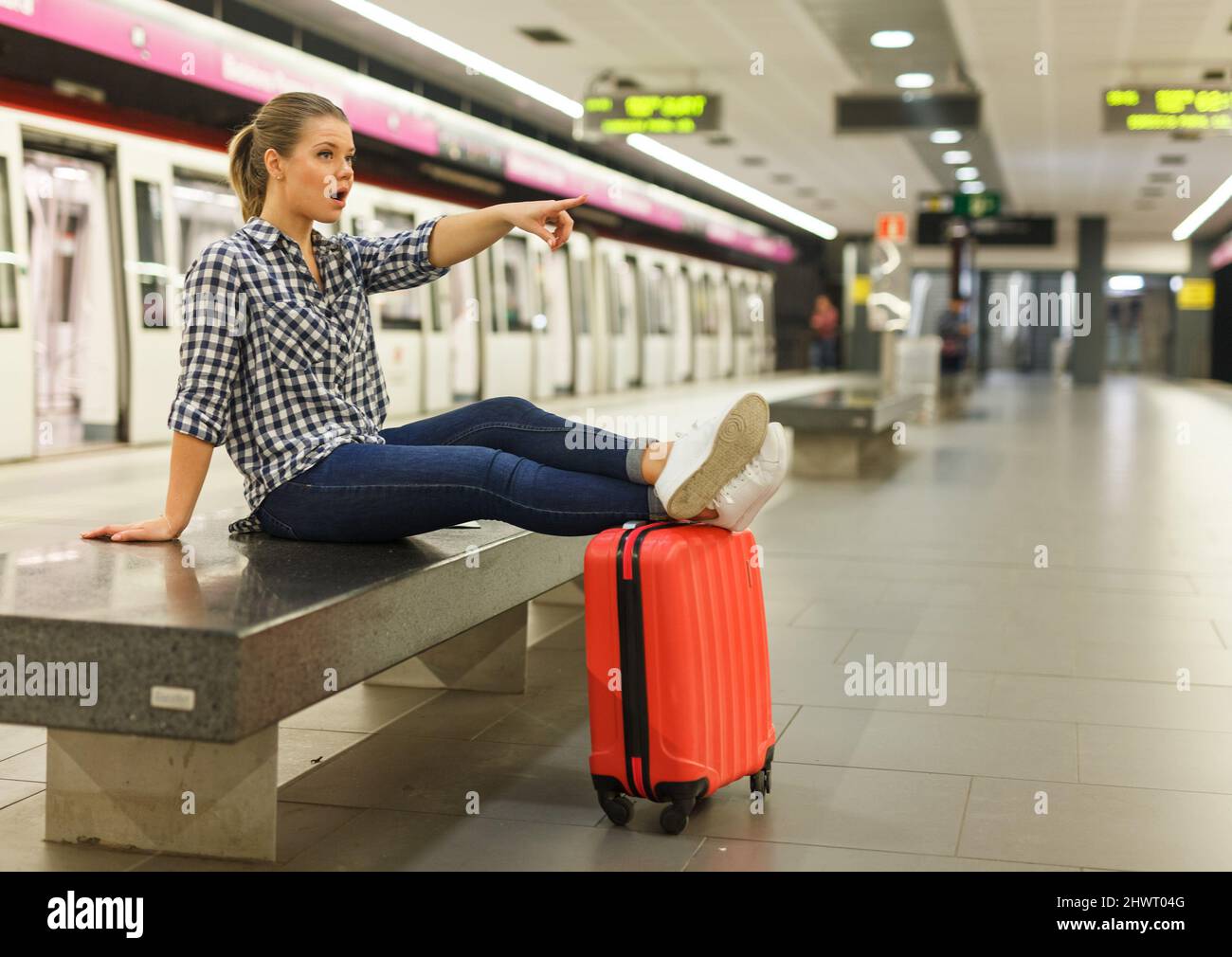Attractive girl traveler waiting for train at metro station sitting on ...