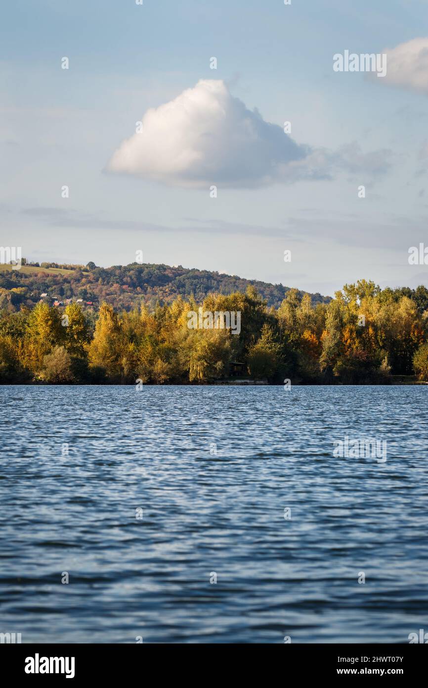 Lake with small waves on water surface in rural landscape. Cloud over ...