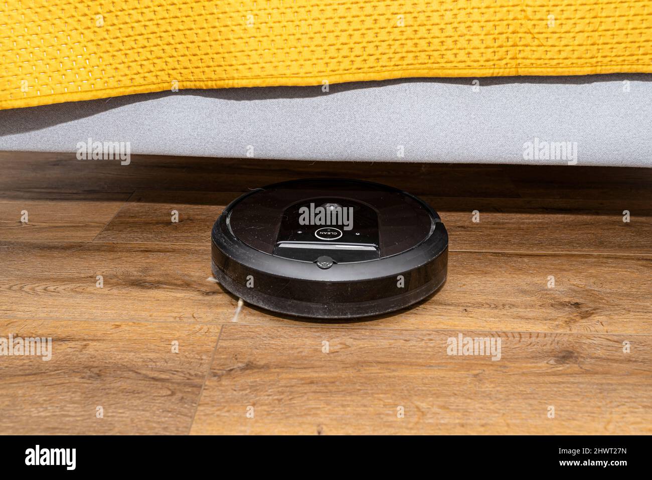 A modern robotic vacuum cleaner cleans the vinyl panels under the bed ...