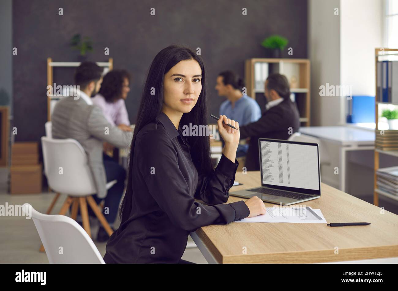 Portrait of serious HR manager sitting at her office desk with laptop ...