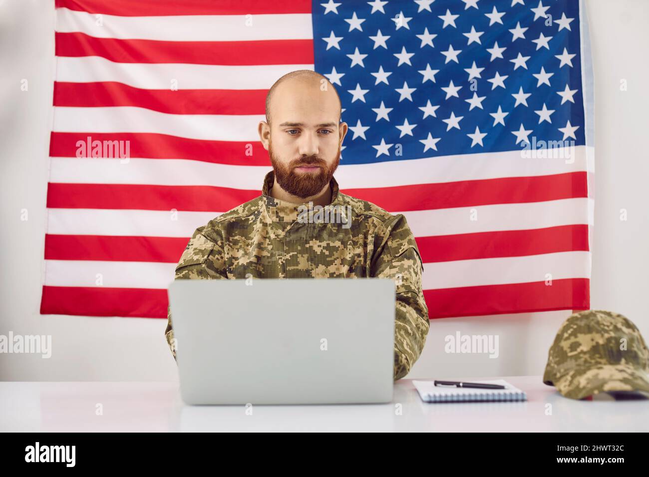 American military student sitting at his desk and working on his laptop ...