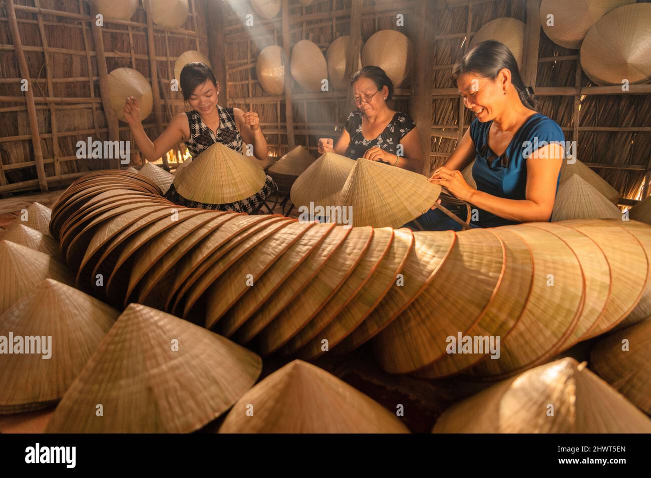 group of vietnamese woman making a traditional conical hat at her home ...