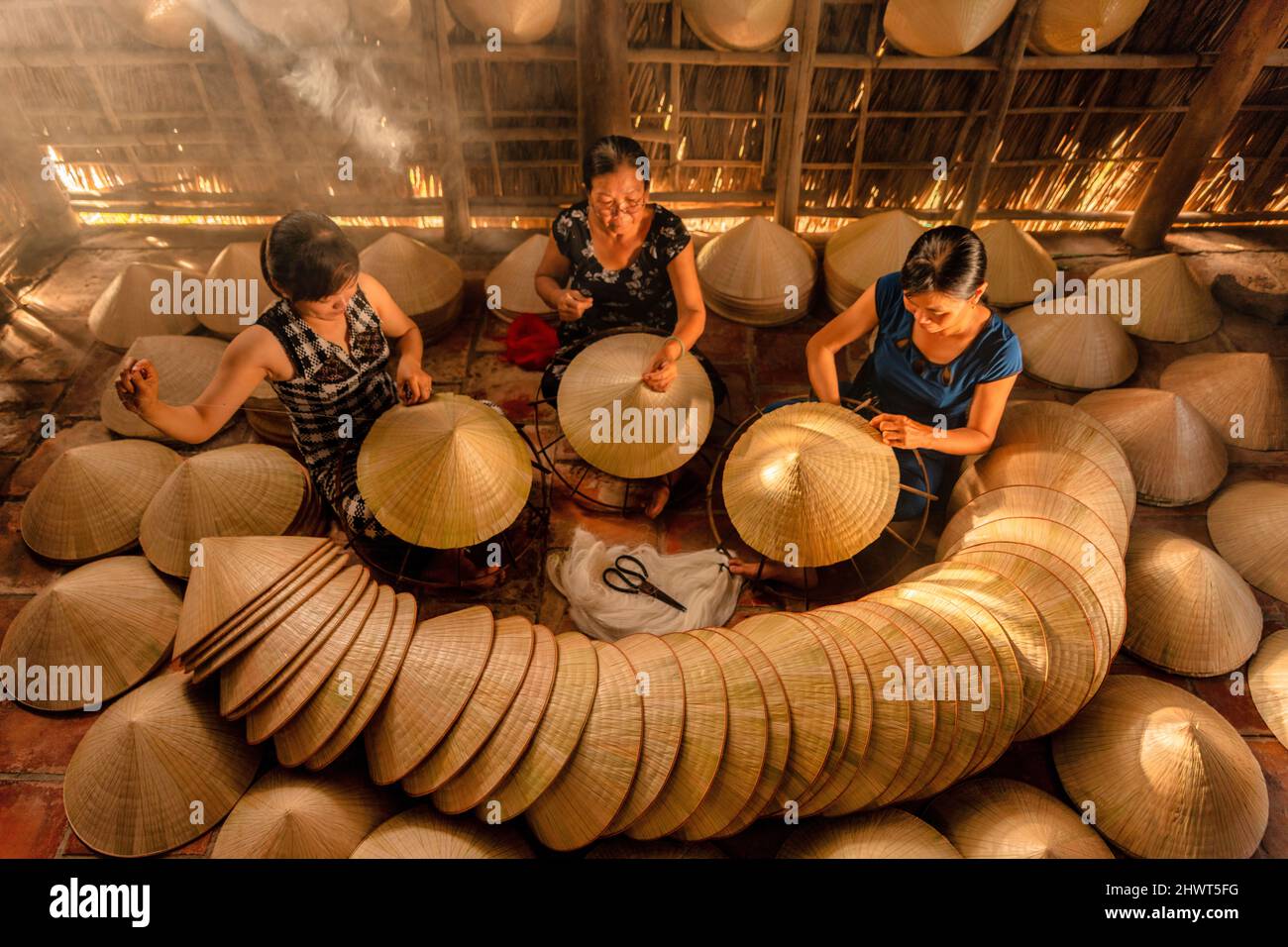 group of vietnamese woman making a traditional conical hat at her home ...