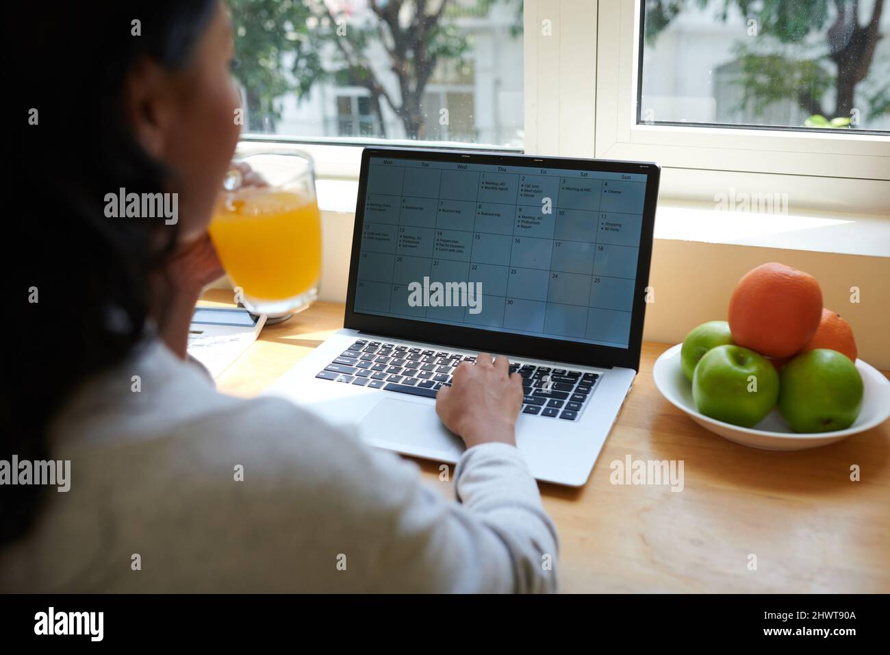 Young woman drinking cup of juice and checking calendar and schedule on ...