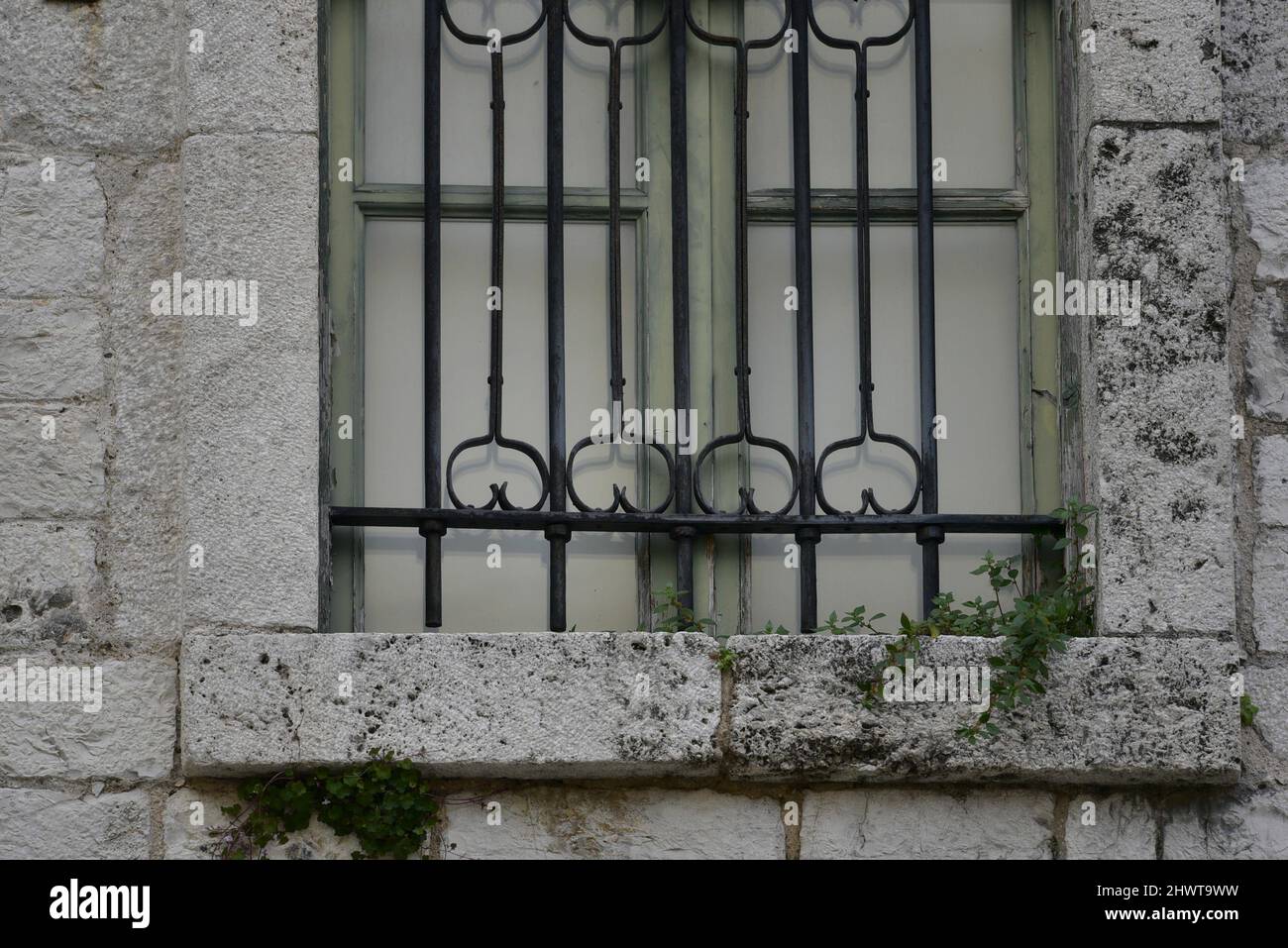 Old historic building window with handcrafted wrought iron grilles on a ...