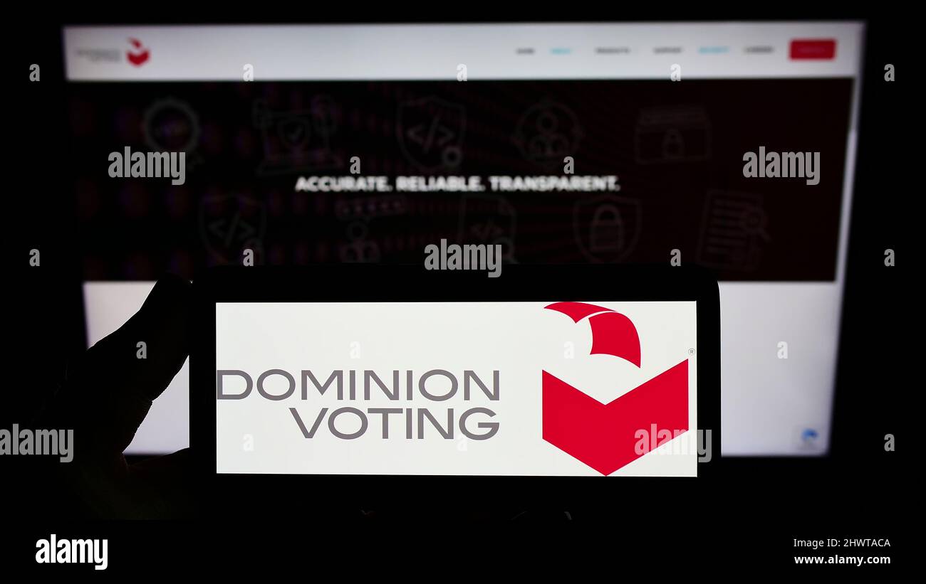 Person holding smartphone with logo of company Dominion Voting Systems ...
