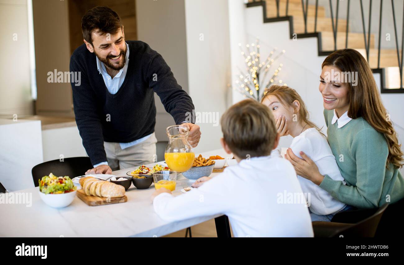 Young happy family talking while having breakfast at dining table at ...