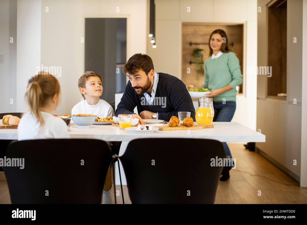 Young mother preparing breakfast for her family in the modern kitchen ...