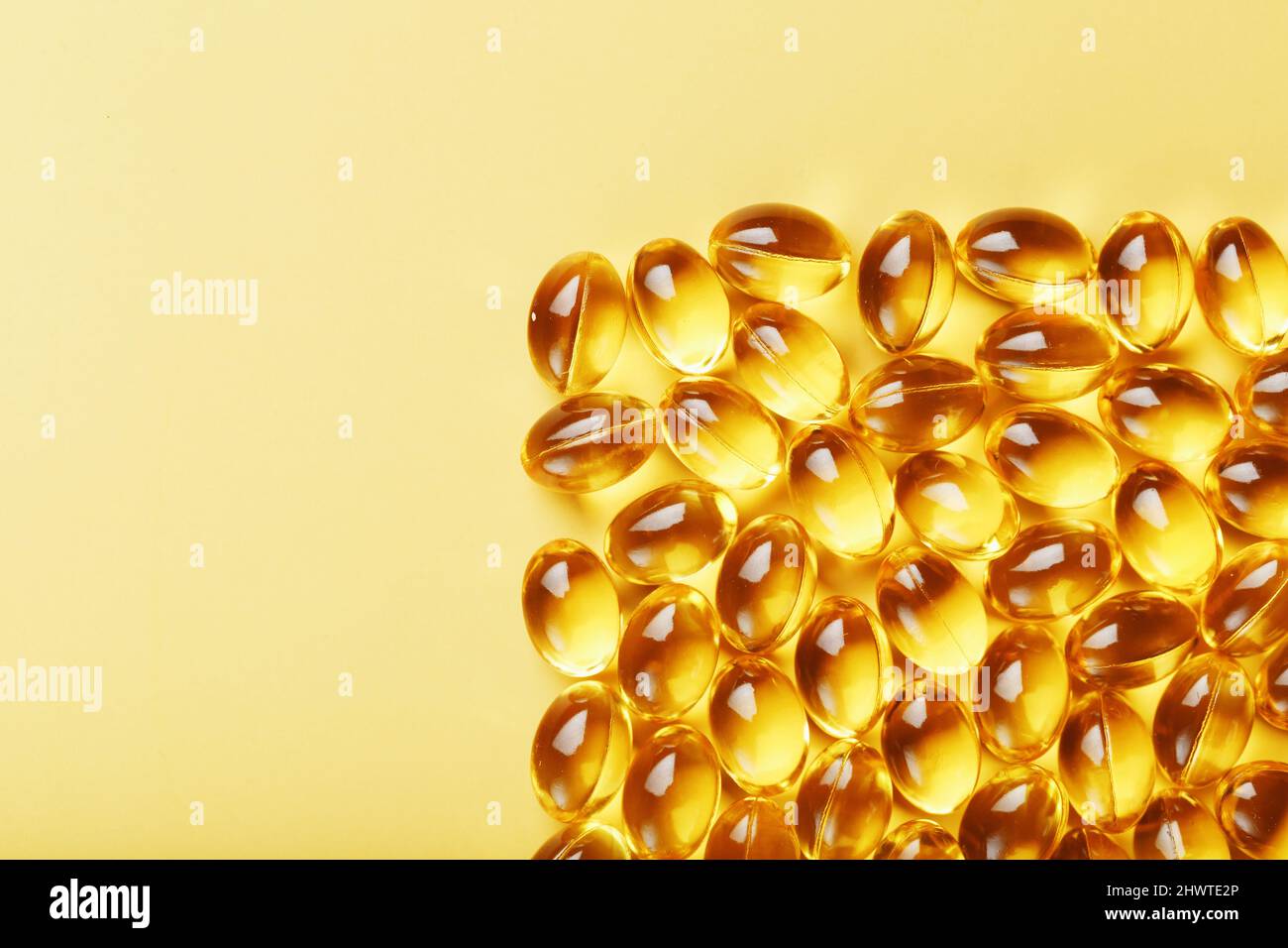 Capsules in a shell with liquid vitamin D3 on a yellow background and a ...