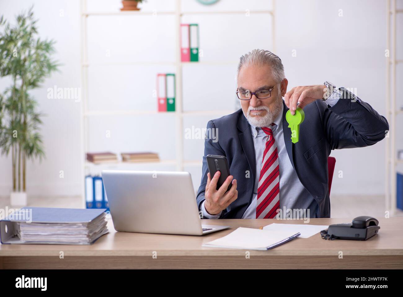 Old businessman employee holding giant key at workplace Stock Photo - Alamy