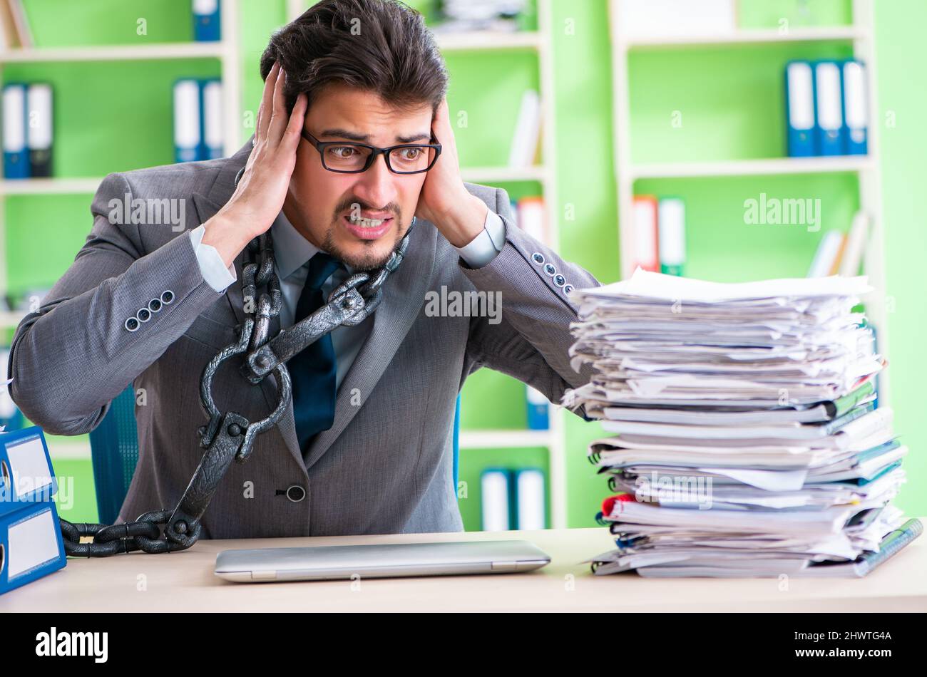 The employee chained to his desk due to workload Stock Photo - Alamy