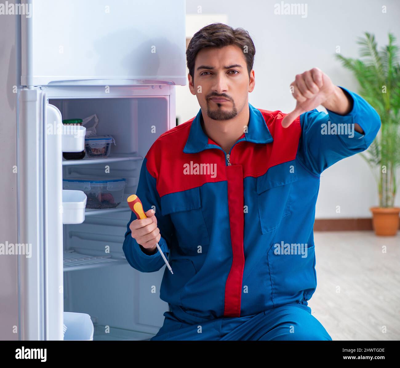 The professional contractor repairing broken fridge Stock Photo - Alamy