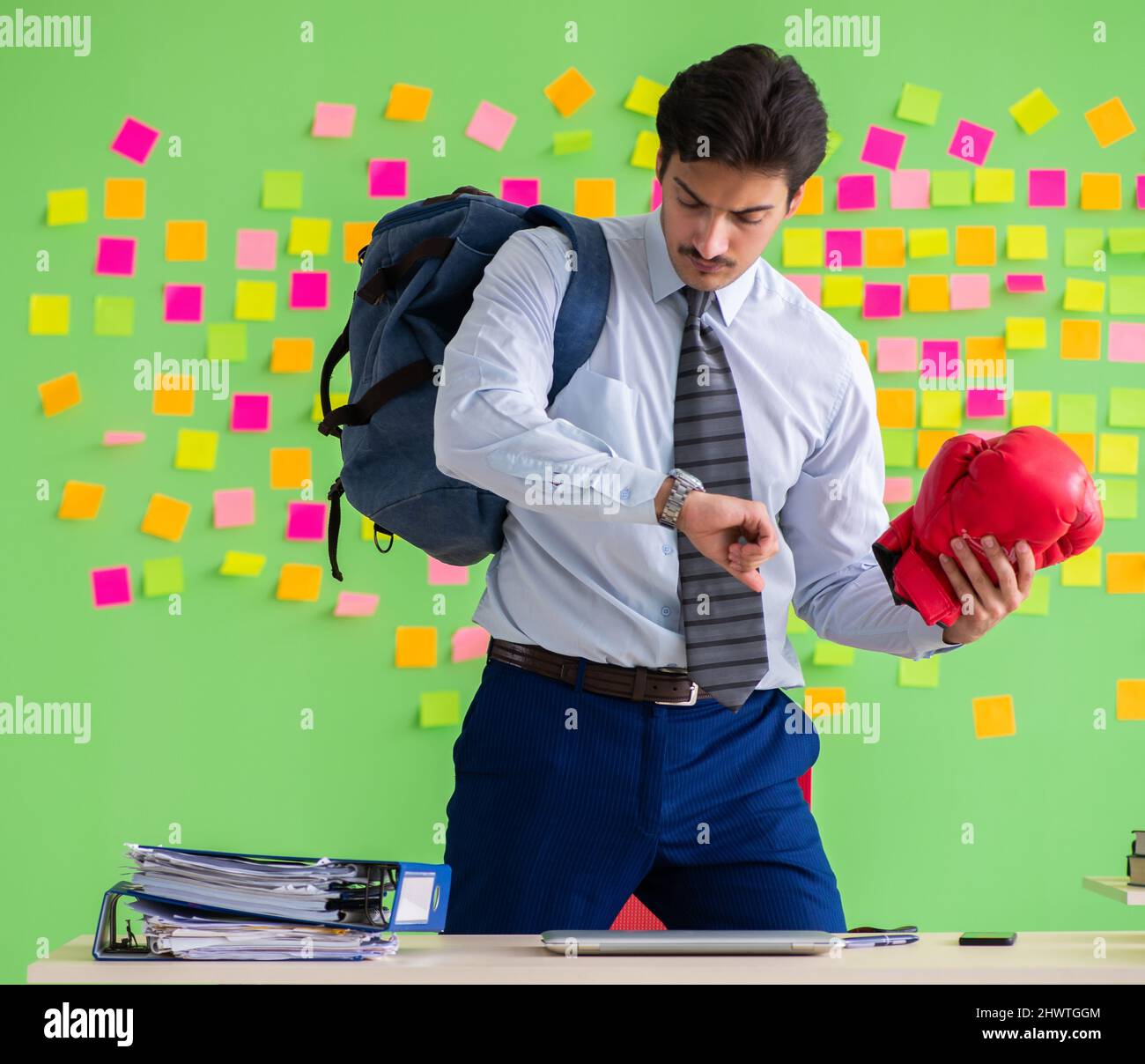Man with boxing gloves in the office with many conflicting priorities ...