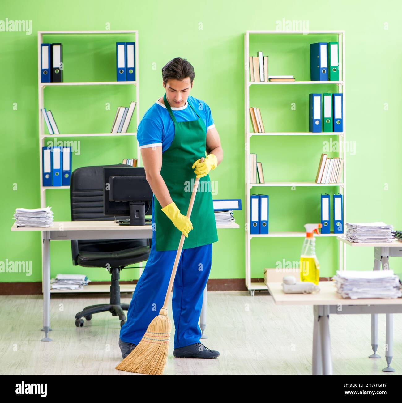 Young male handsome professional cleaner cleaning floor with broom ...