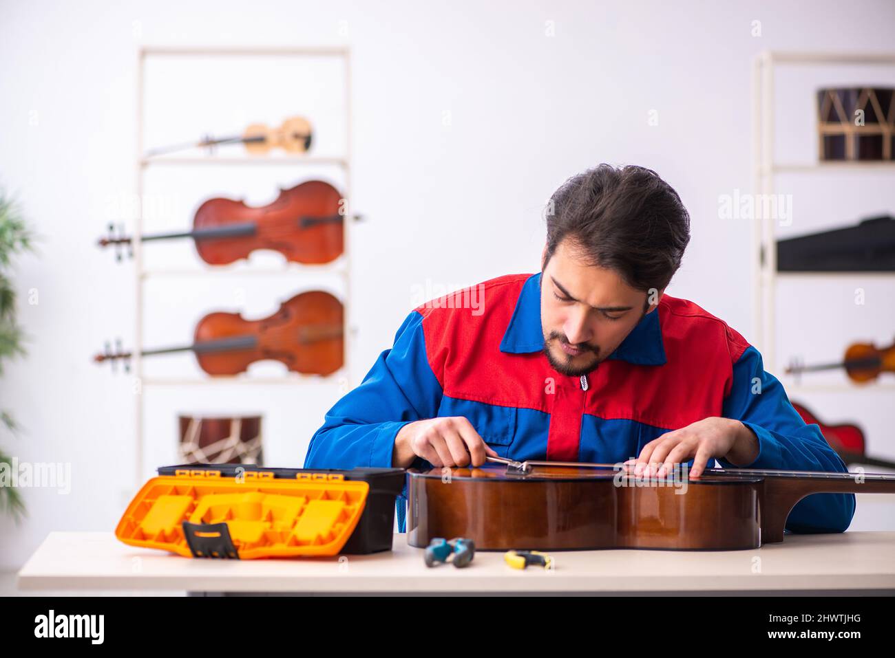 Young repairman repairing musical instruments at workplace Stock Photo ...