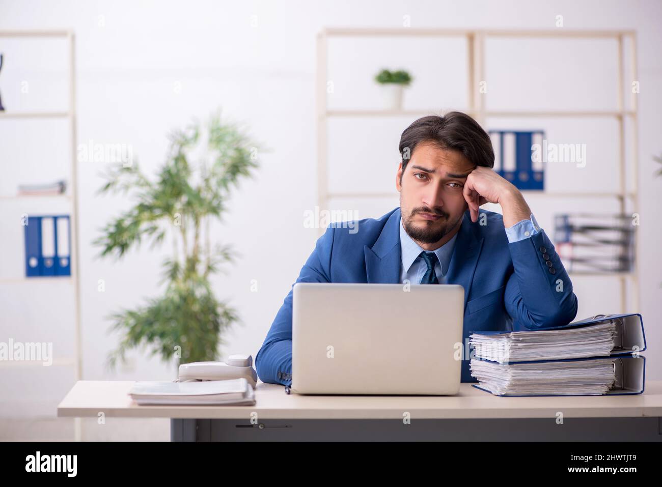 Young employee and too much work in the office Stock Photo - Alamy