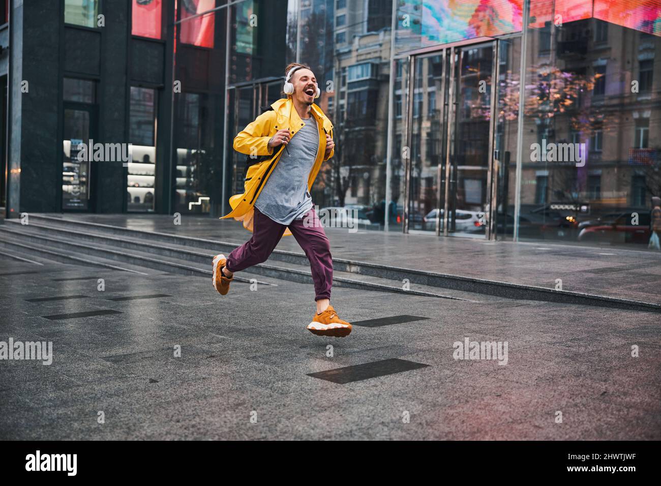 Joyful young man hurrying with rucksack in centre Stock Photo - Alamy