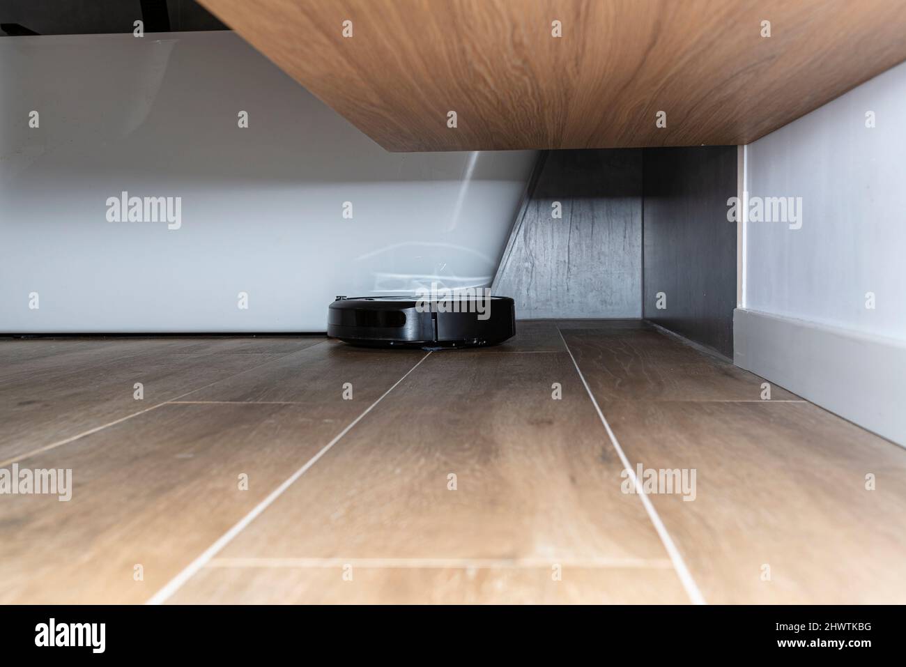 A modern robotic vacuum cleaner cleans the ceramic tiles in the ...