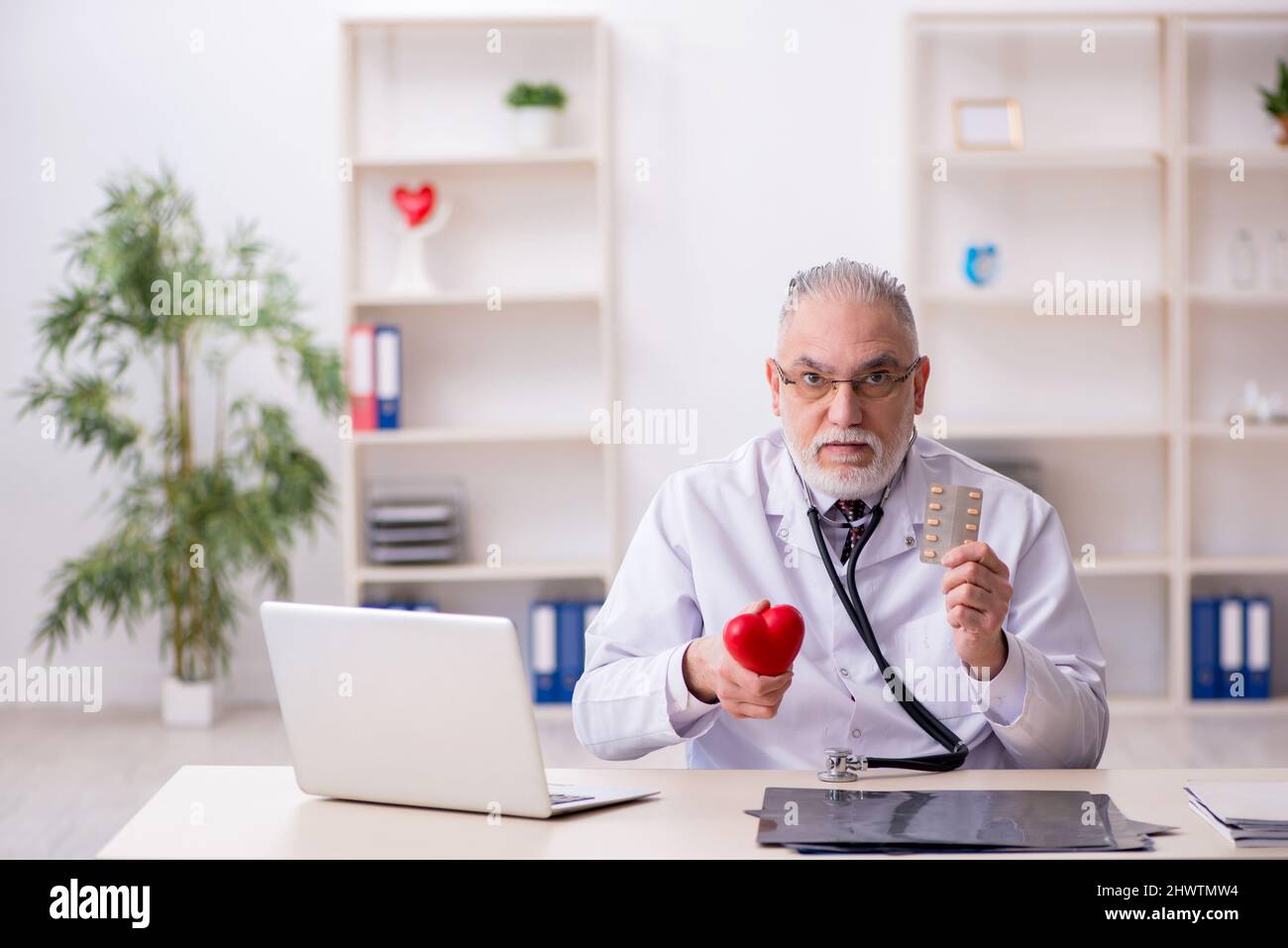 Old doctor cardiologist working in the clinic Stock Photo - Alamy