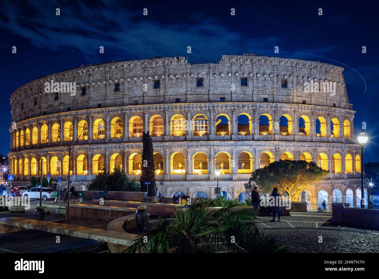 Night view of the Colosseum illuminated with warm yellow light, against ...