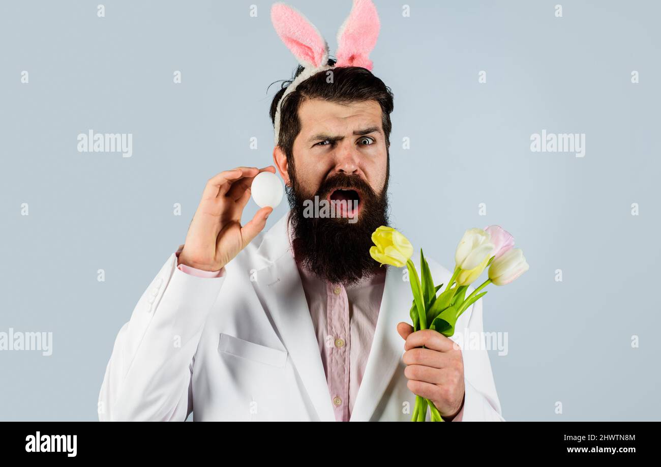 Easter celebration. Surprised bearded male in suit with egg and flowers ...