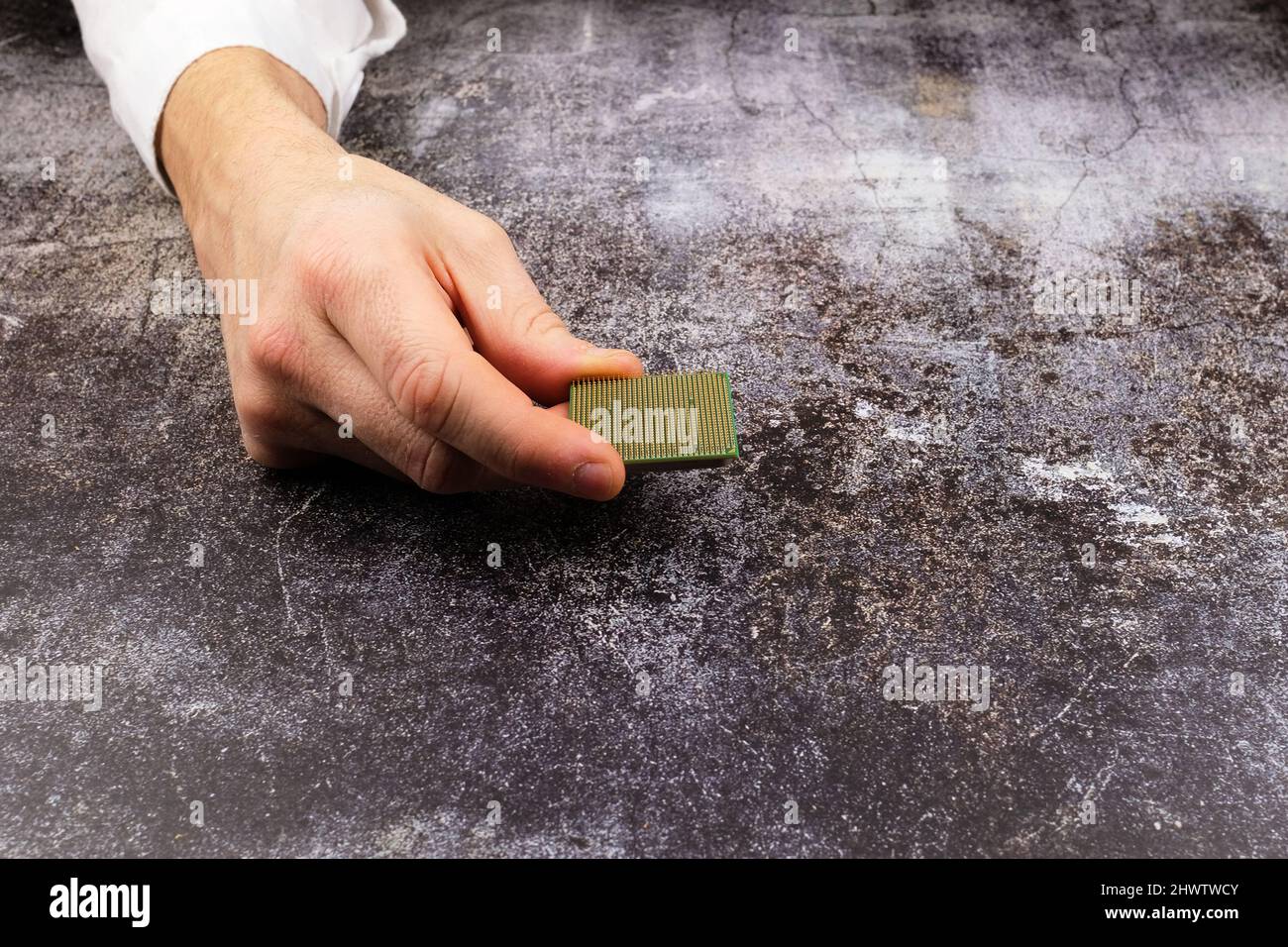 Man's hand showing a microchip on a table with a color like cement ...