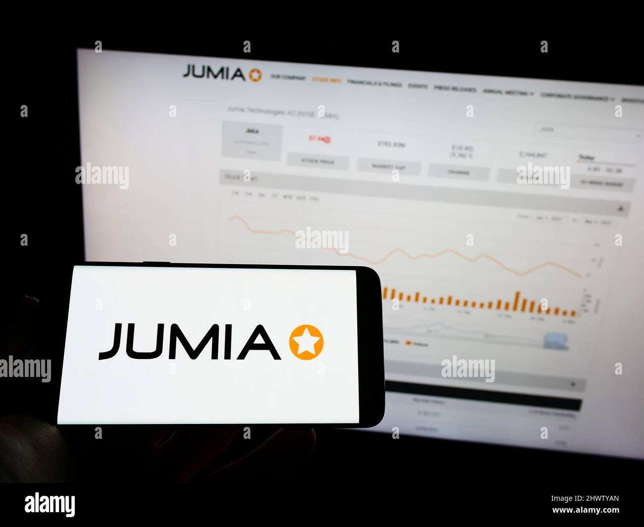Person holding mobile phone with logo of Nigerian company Jumia Technologies on screen in front ...
