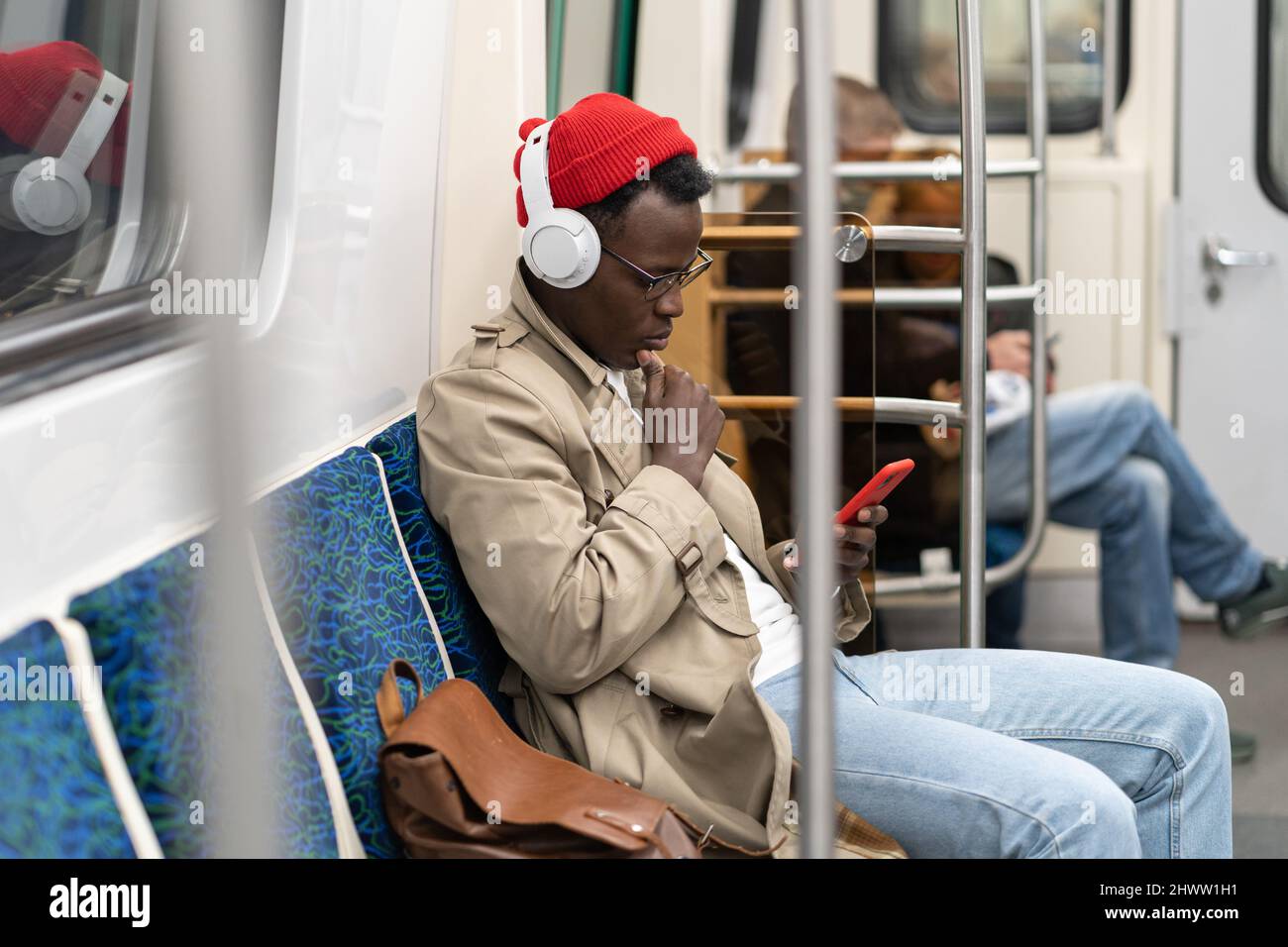 Pensive African young man reading posts, listening music, using ...