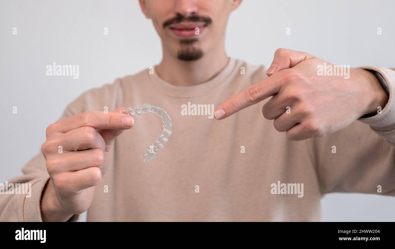 Adult man pointing hand to dental aligner retainer for beautiful teeth ...