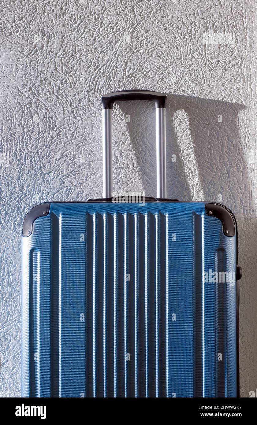 Big blue suitcase stays in the room in hotel near wall with sunlight ...