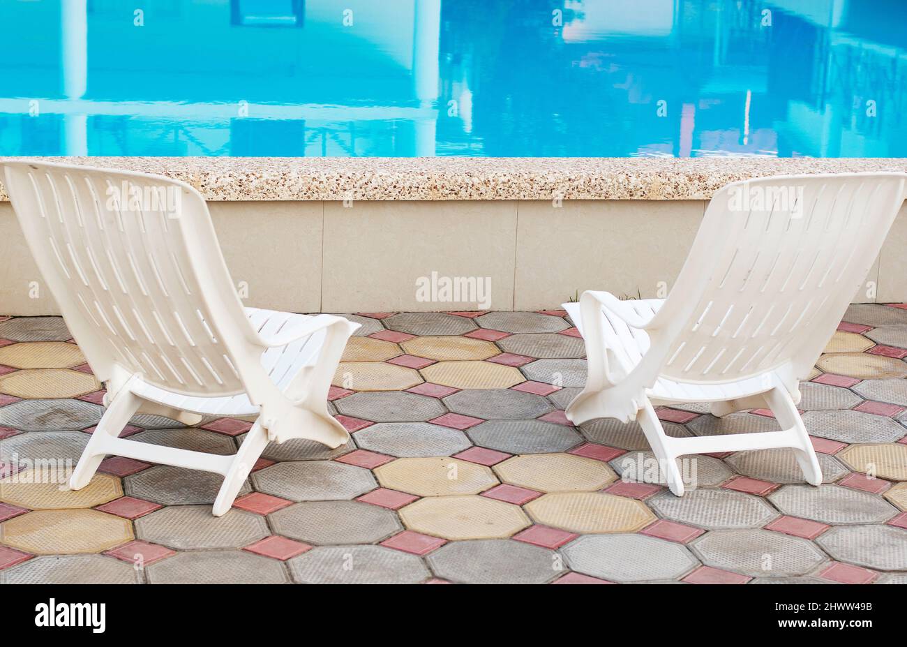 Clean swimming pool and empty resting chairs Stock Photo - Alamy