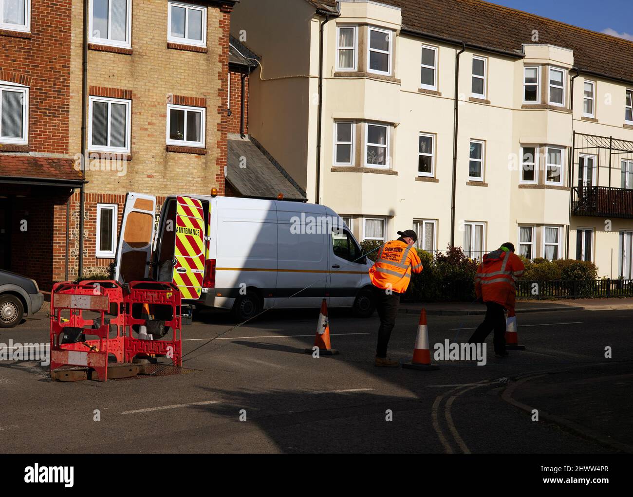 Two workmen pulling a telephone wire from a box on street level Stock ...