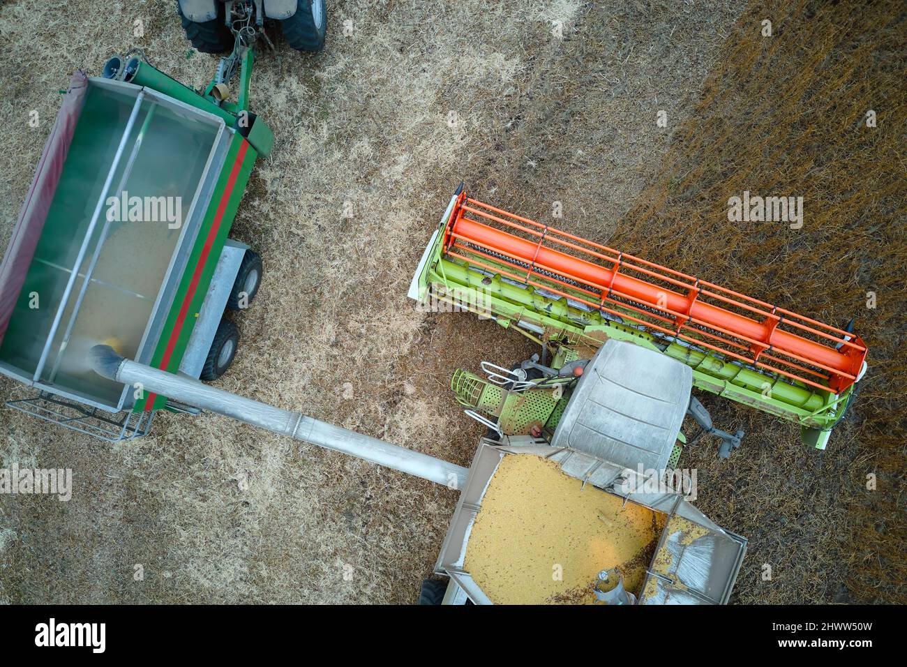 Aerial view of combine harvester unloading grain in cargo trailer ...