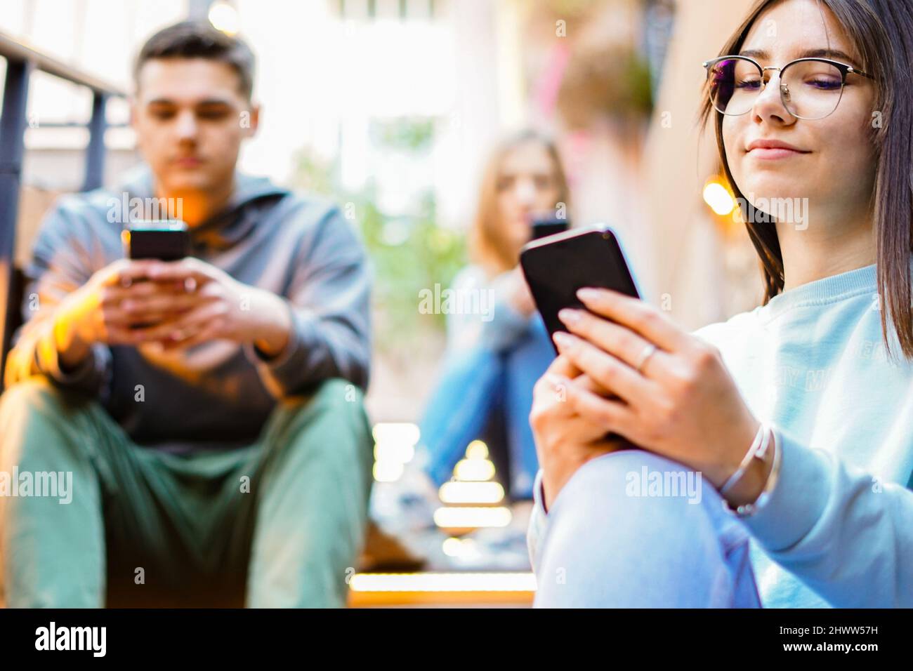 Group of friends using cellphones - Students sitting in a stairs and ...